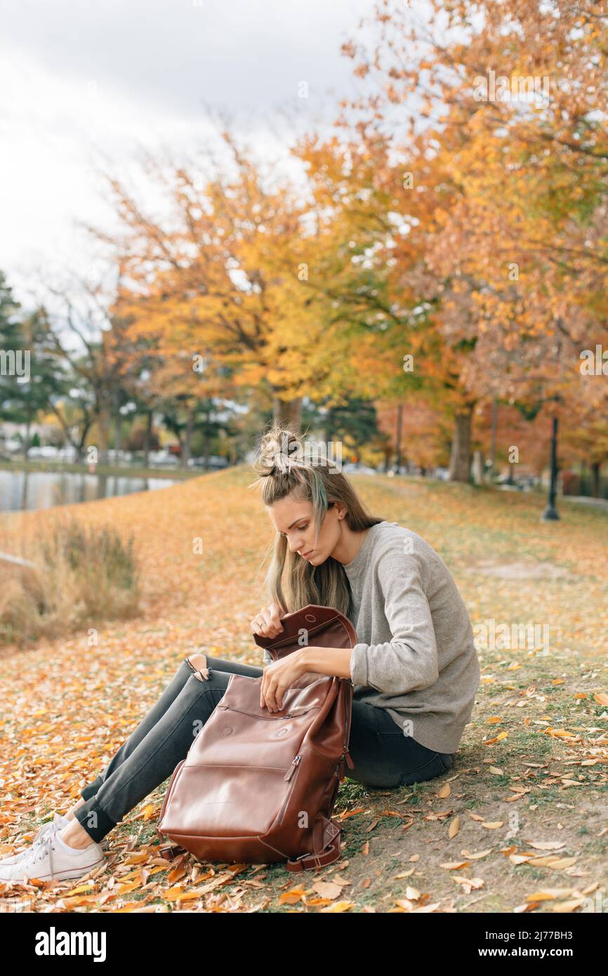woman wearing neutral colors sitting outside in the fall looking Stock ...