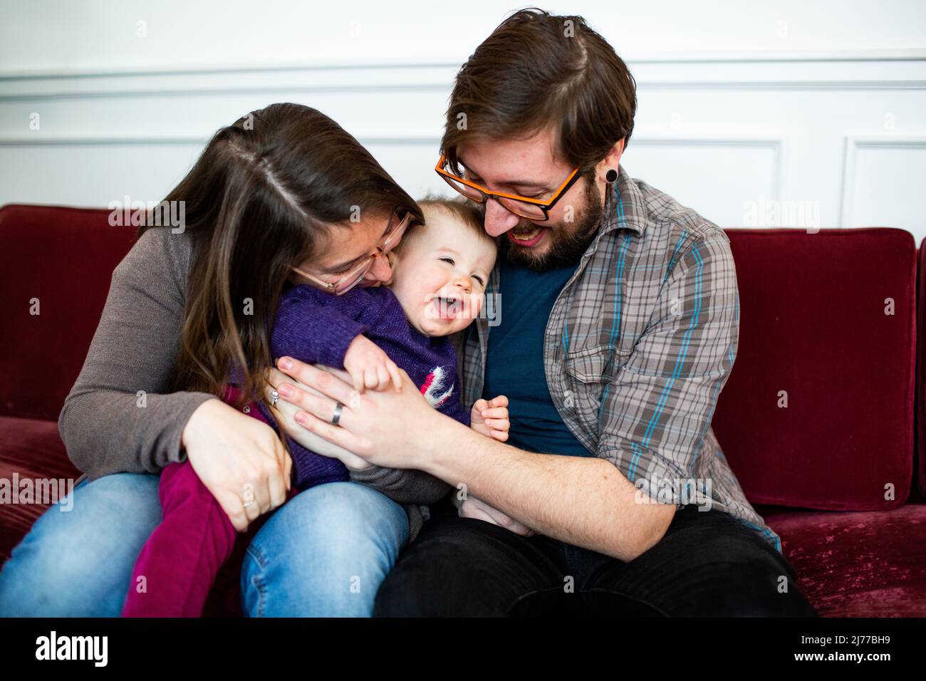 Parents Hug Their Daughter as She Laughs Stock Photo - Alamy