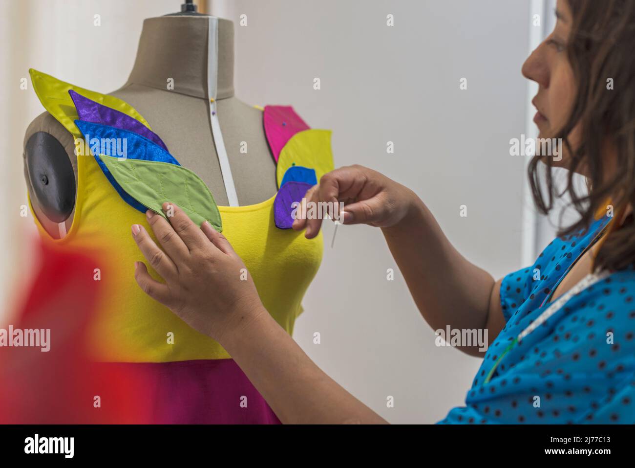 Latin fashion designer creating a dress on a mannequin using needles ...