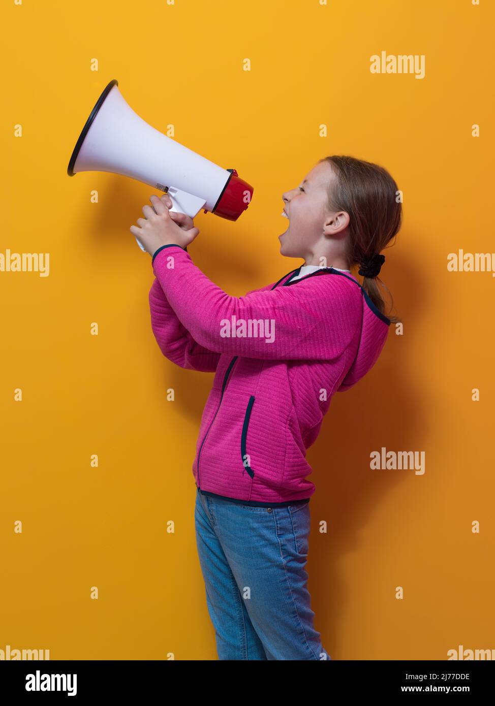 Funny little kid girl Screaming in megaphone over the yellow background ...