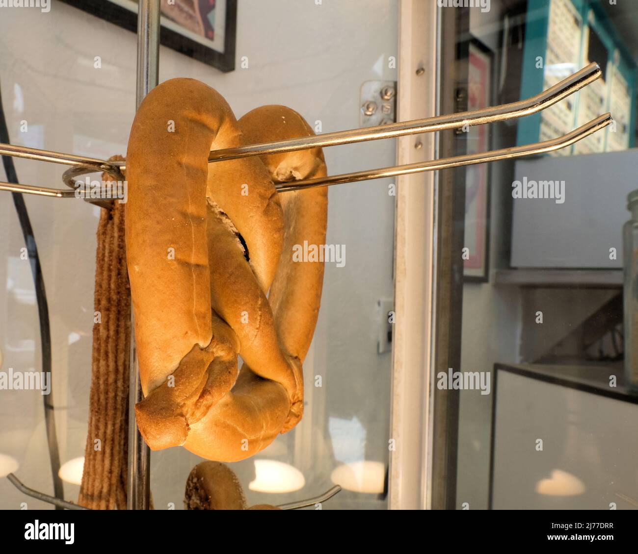 A plain, unsalted pretzel in a glass case with a heating element; warm ...