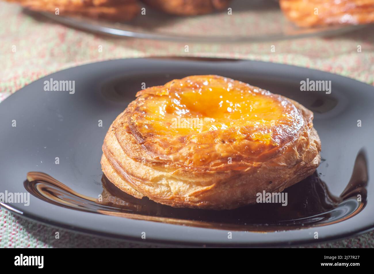 Sweet puff pastry stuffed with apricot and peach on a black dish with ...