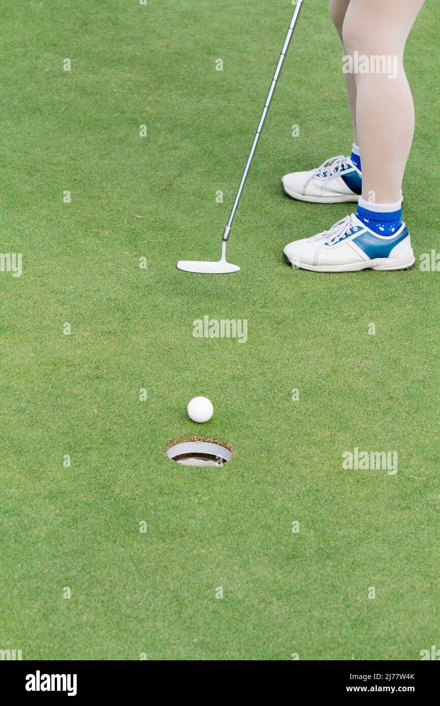 Woman golf player putting on the green Stock Photo - Alamy