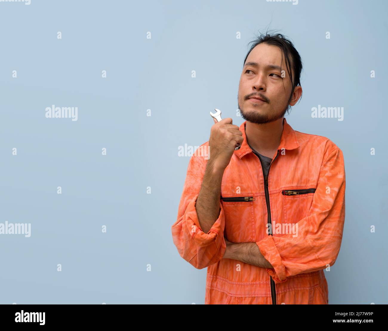 The chief mechanic in an orange uniform held a small wrench. Standing ...