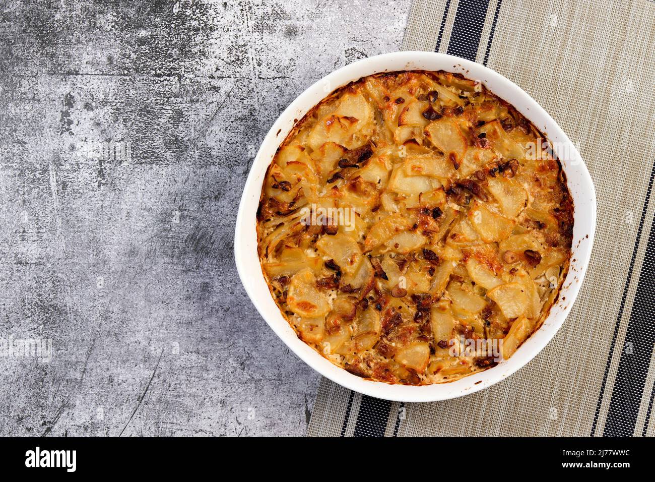 Oven baked potatoes with cheese, mushrooms and onions in a white baking ...