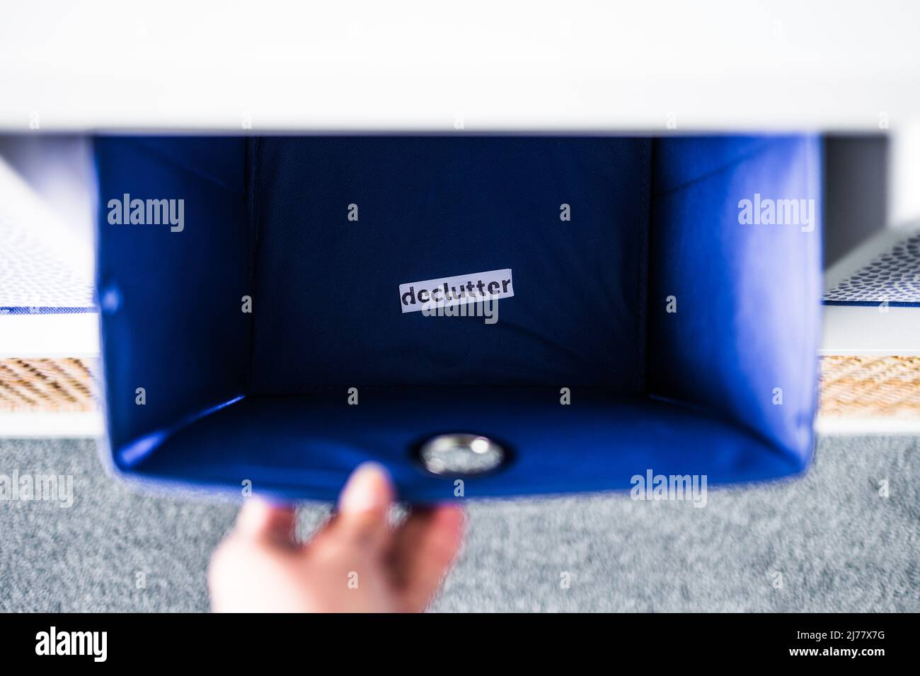 hand grabbing storage cube with Declutter label inside of it with ...