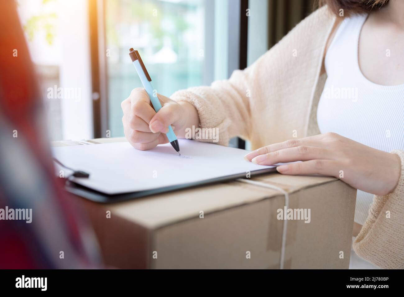 Close up Delivery man in red uniform holding package while client woman ...