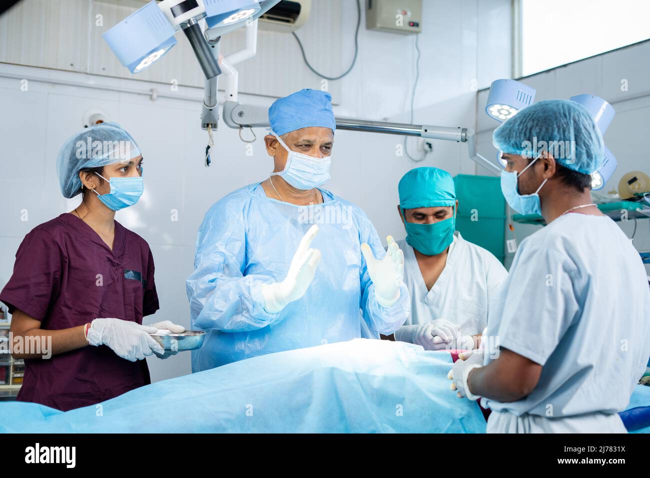 Senior surgeon assisting fellow practitioners at operation theater ...