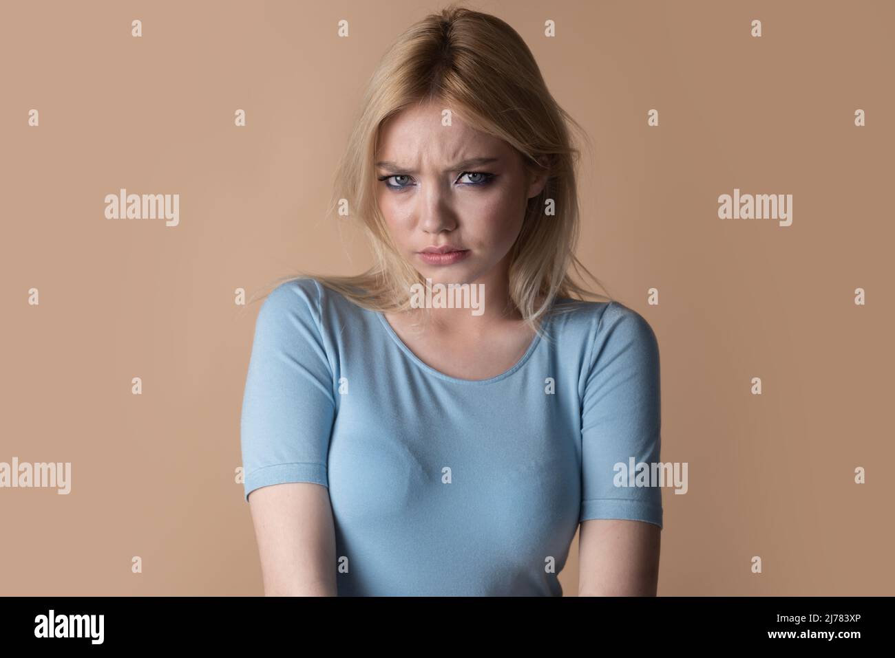 Studio portrait of young angry woman with blue eyes. Sad girl face ...