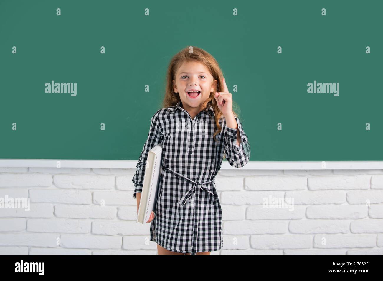Portrait of school girl nerd student hold book with surprising ...