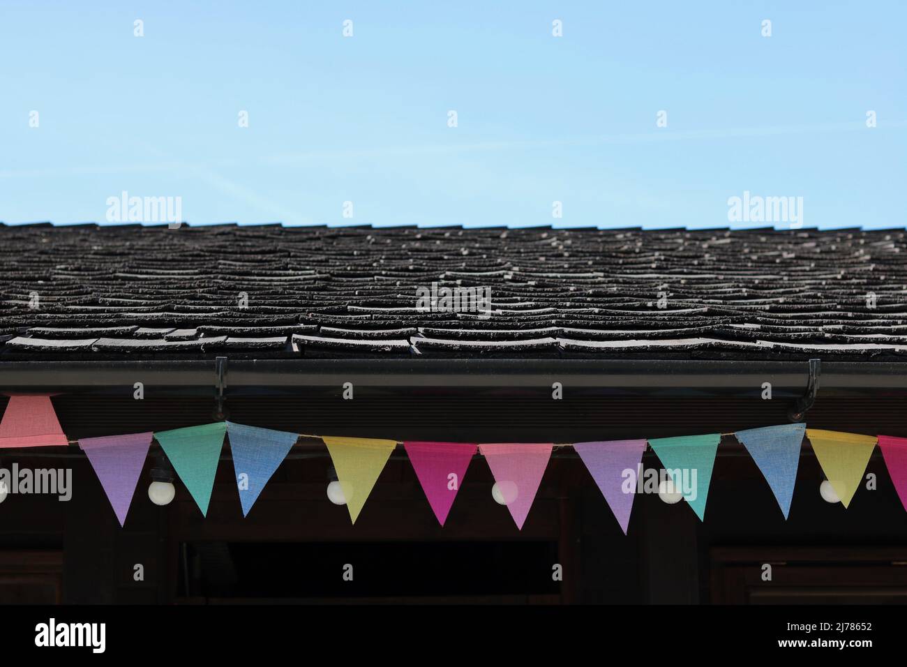 String of bunting in various pastel colours below roof and sky Stock ...