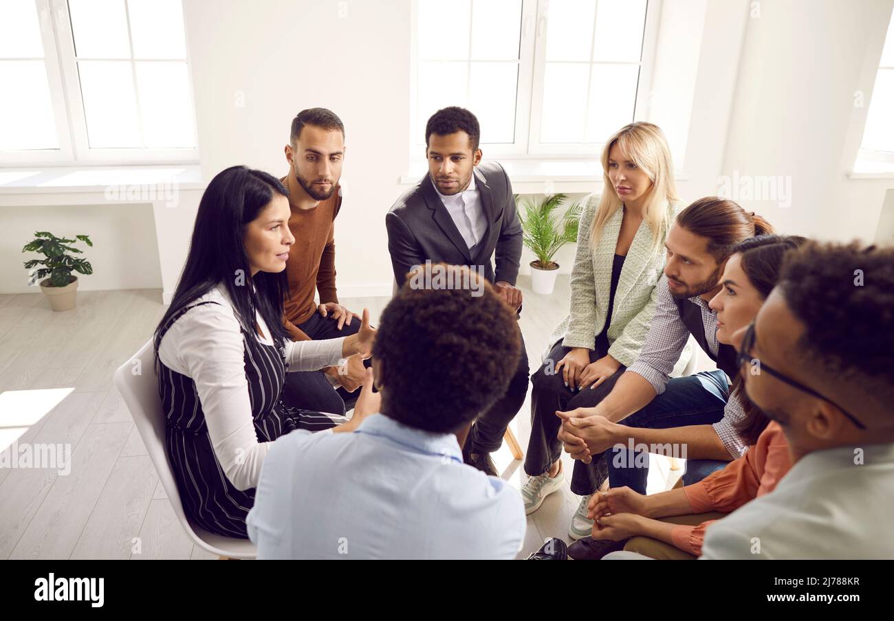 Professional business coach talking about teamwork with a team of young ...