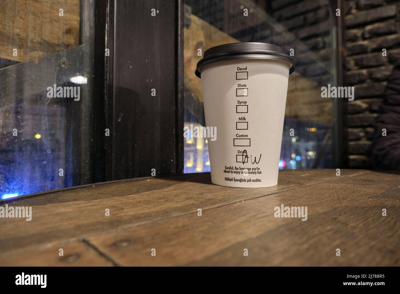 Inside a cafe, coffee cup standing at wooden table in cafe at night ...