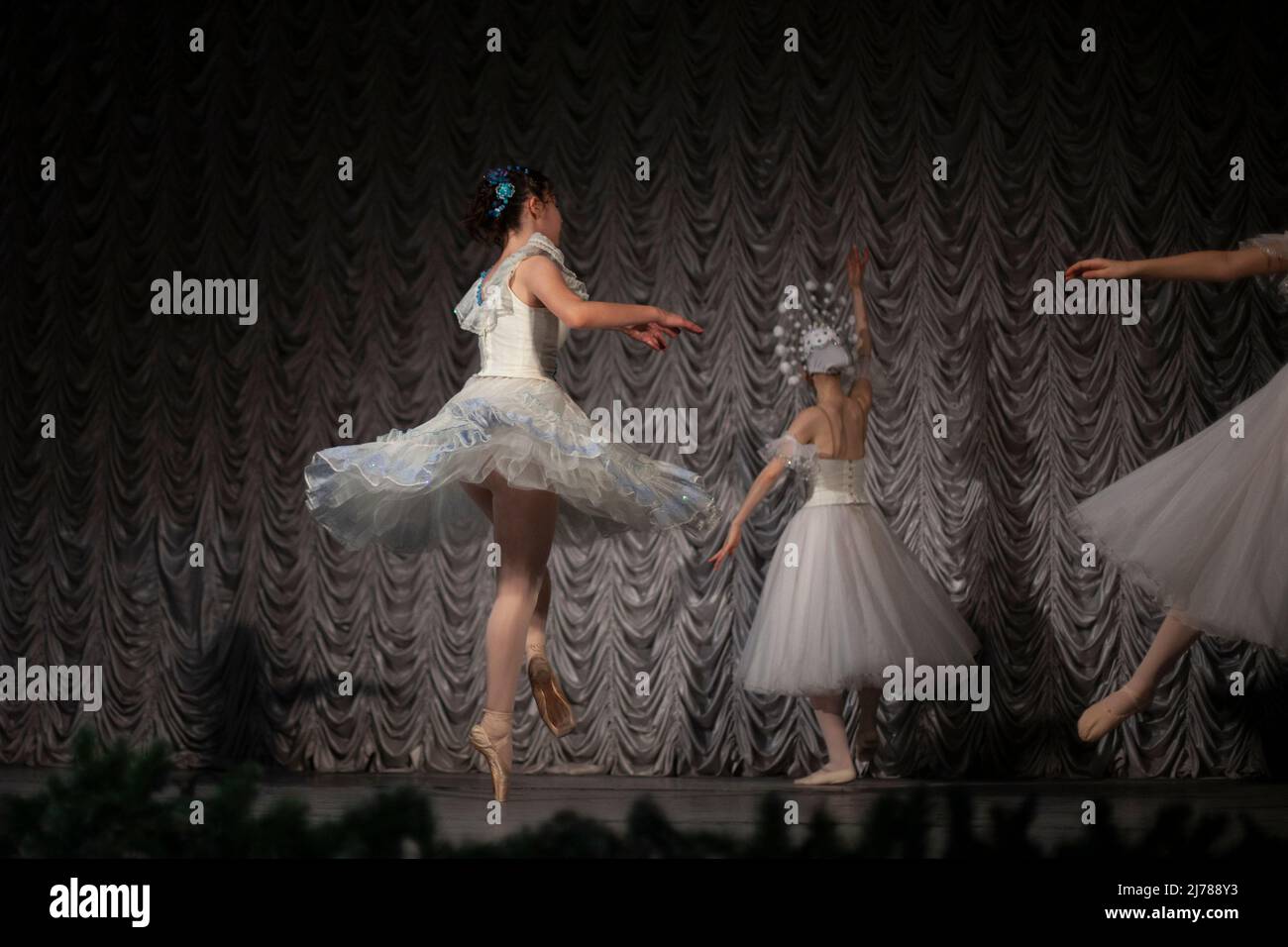 The girl is dancing on stage in a white dress. The artist is performing ...