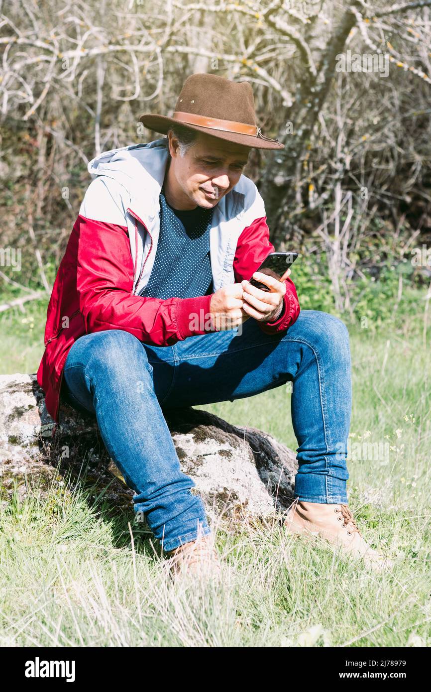 Entrepreneurial self-employed man wearing hat, looking at his mobile ...