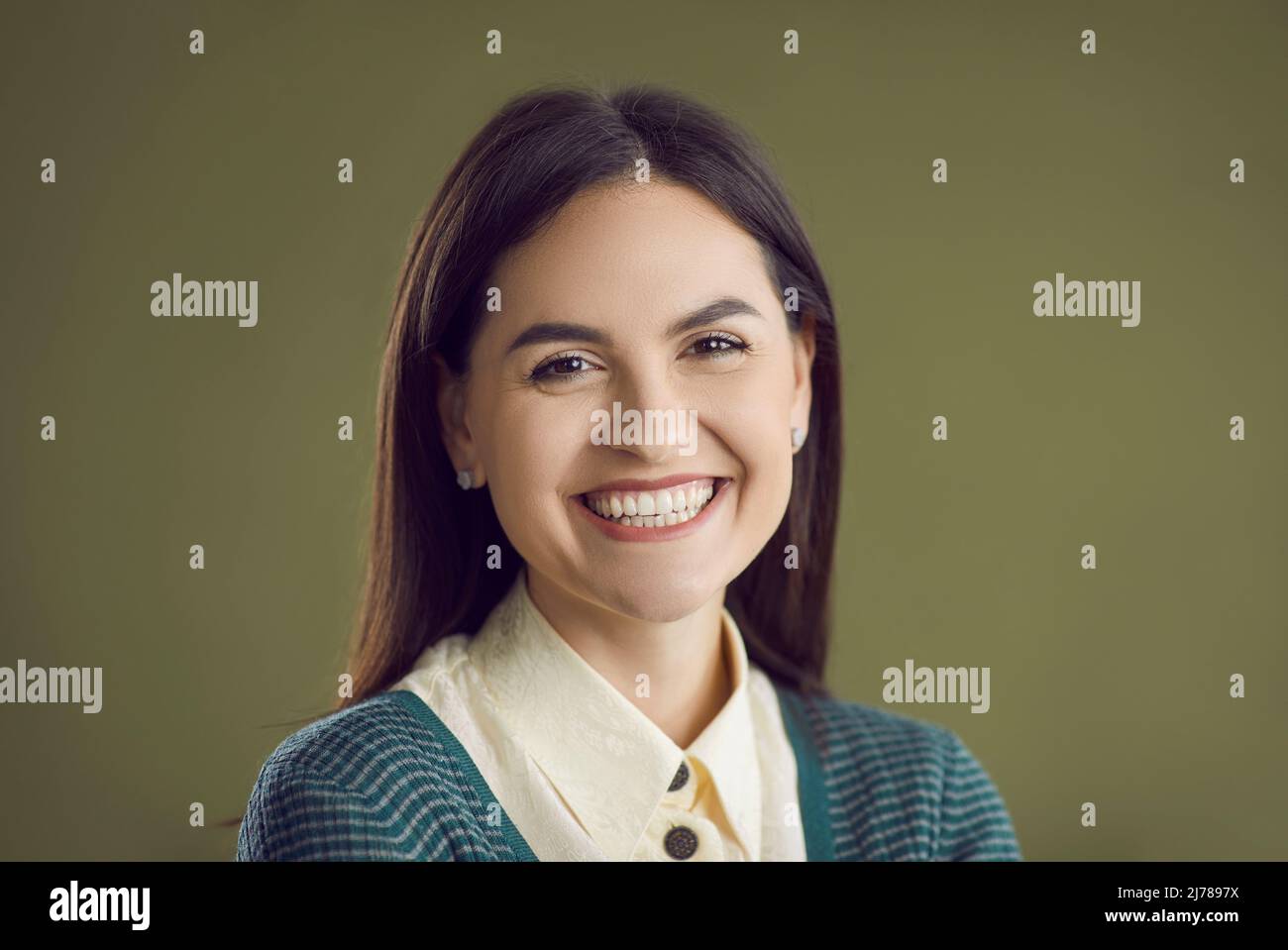 Headshot of happy young woman with beautiful smile against green studio ...