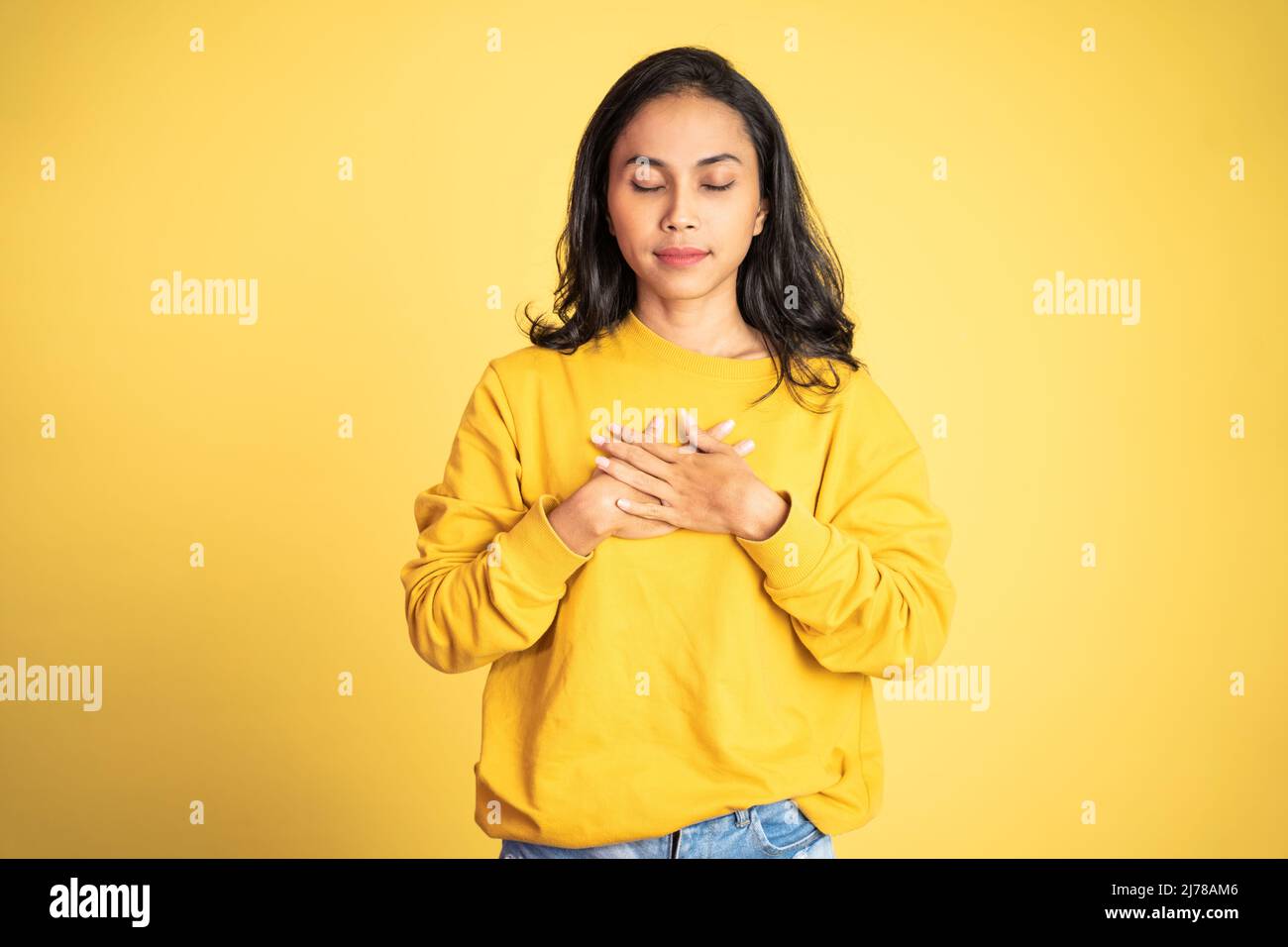 Asian young woman holding chest while feeling relieved Stock Photo - Alamy
