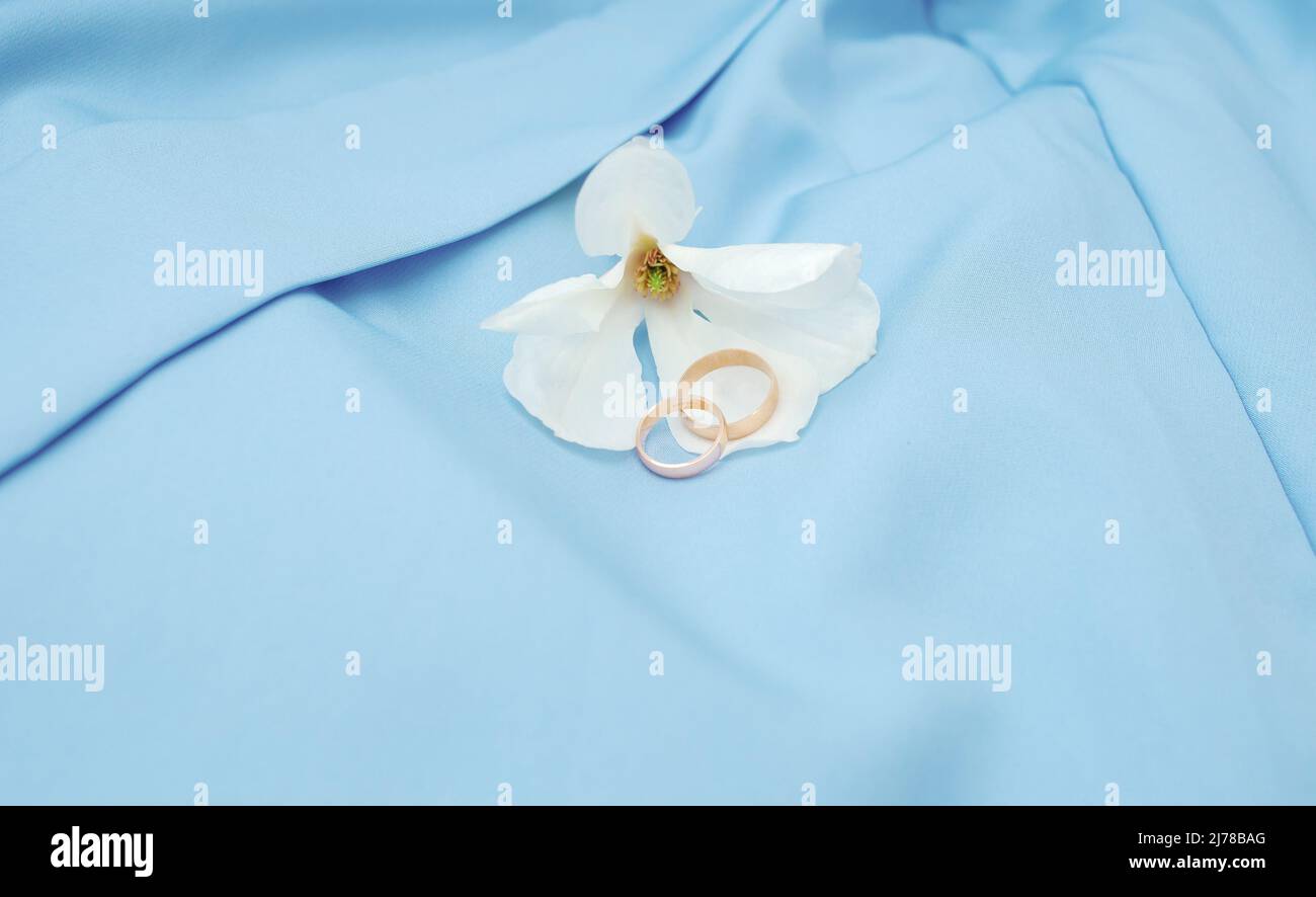Wedding rings on a blue background. White magnolia flower Stock Photo ...