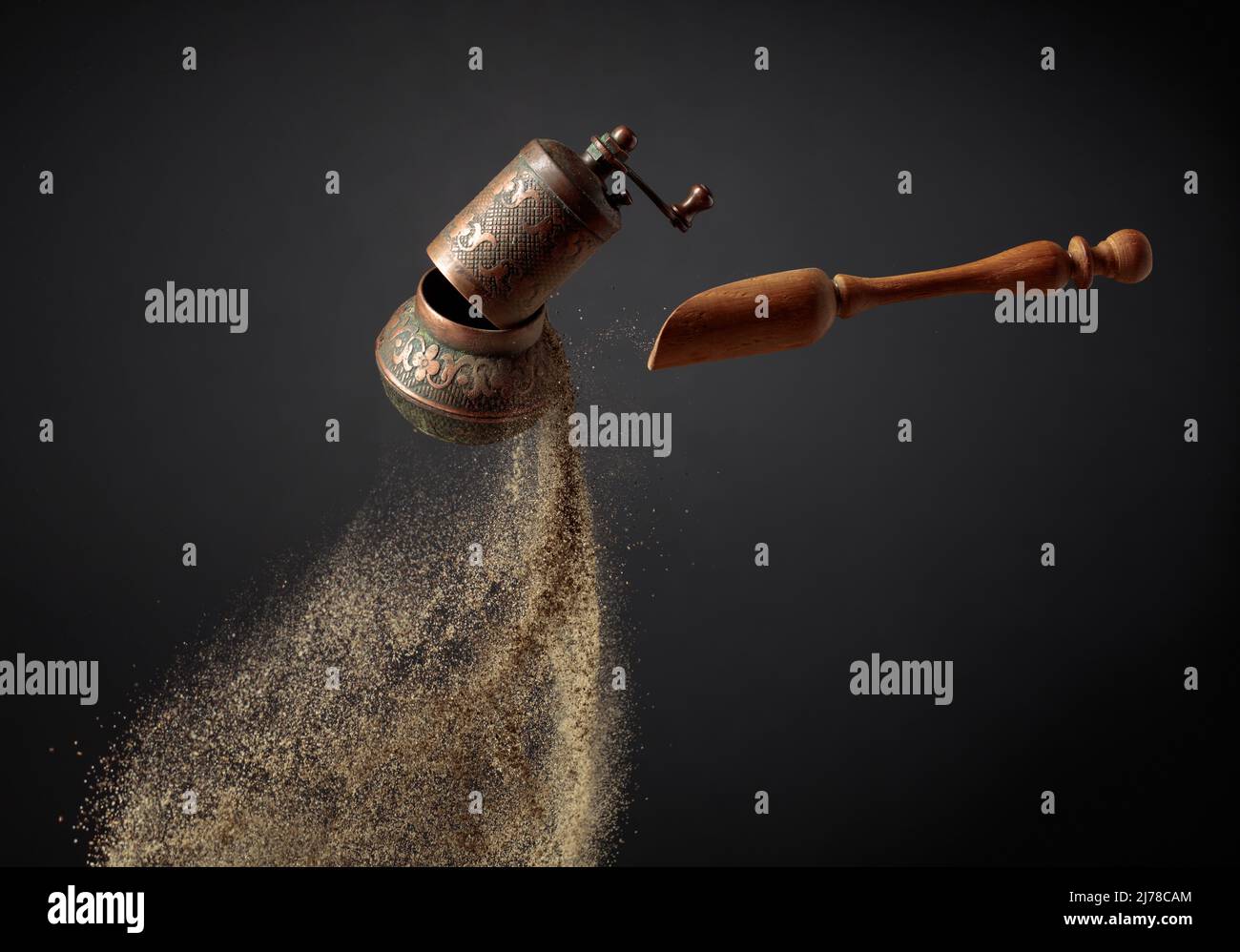 Pepper powder is poured out of the wooden spoon. Old copper pepper ...