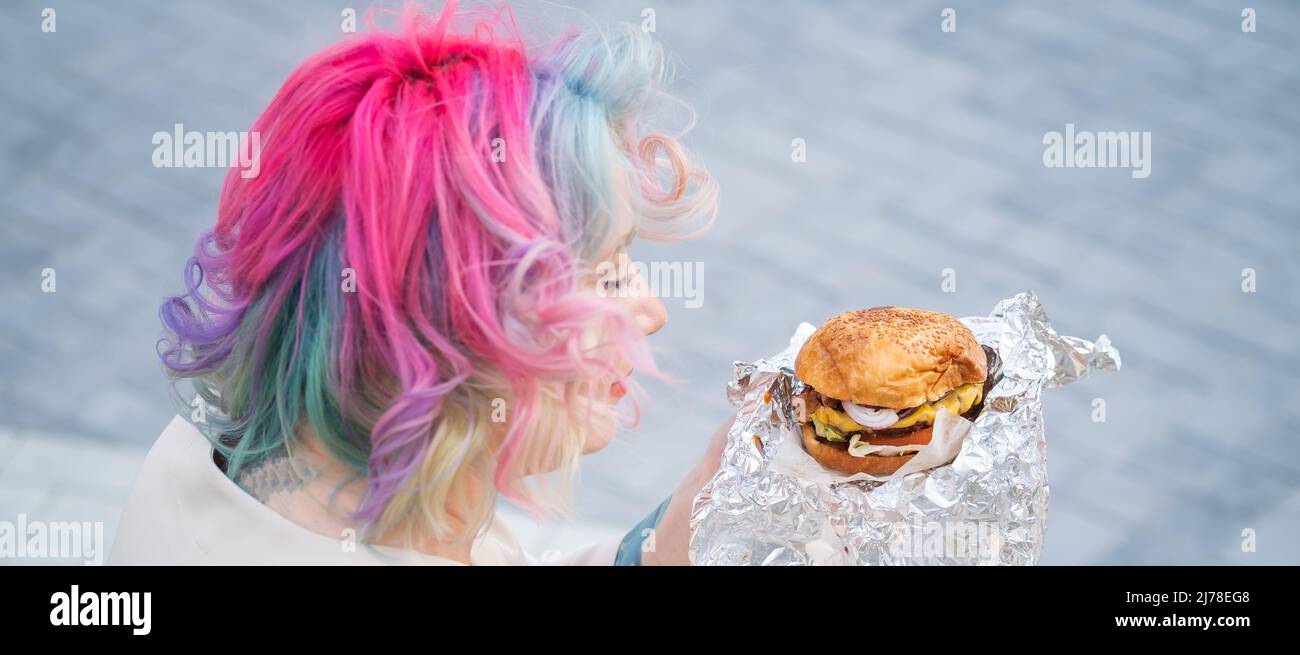 Caucasian woman with curly colored hair eating burger. Bad eating ...
