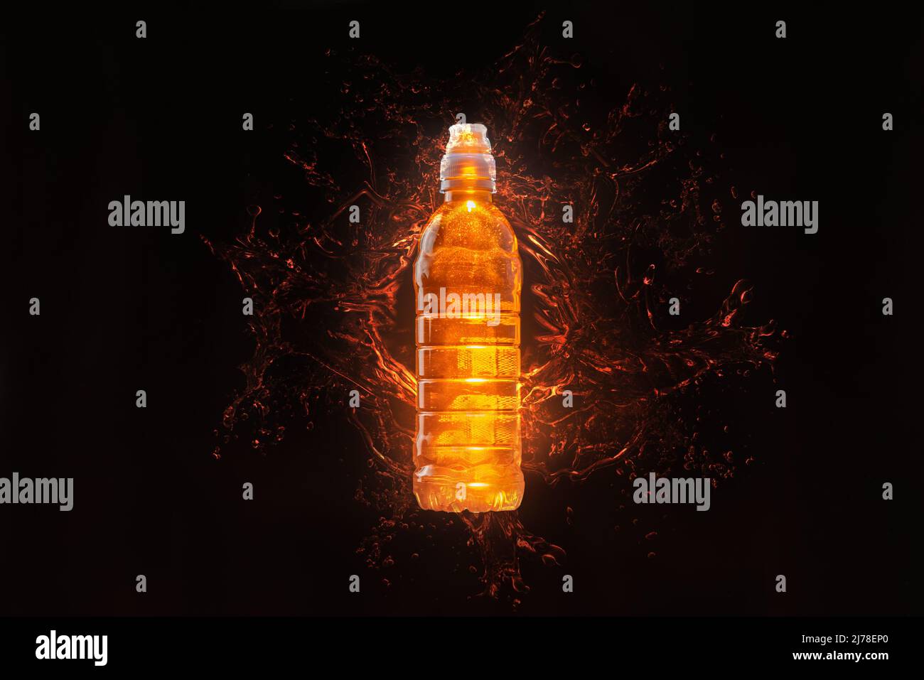 Isotonic energy drink. Orange bottle on black background with splashes ...