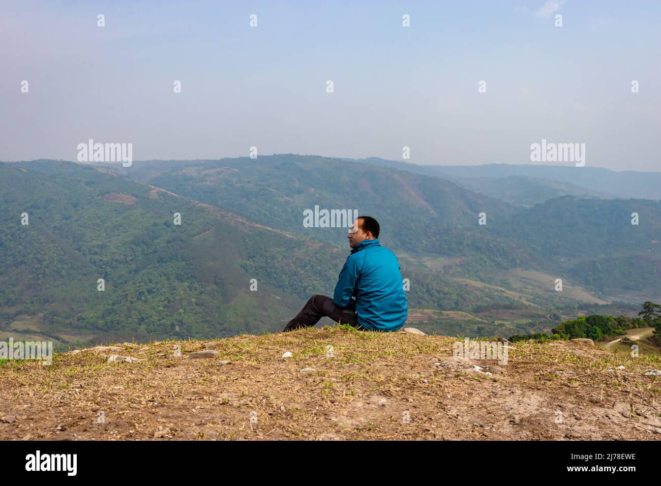 man sitting alone at hill top with misty mountain rage background from ...