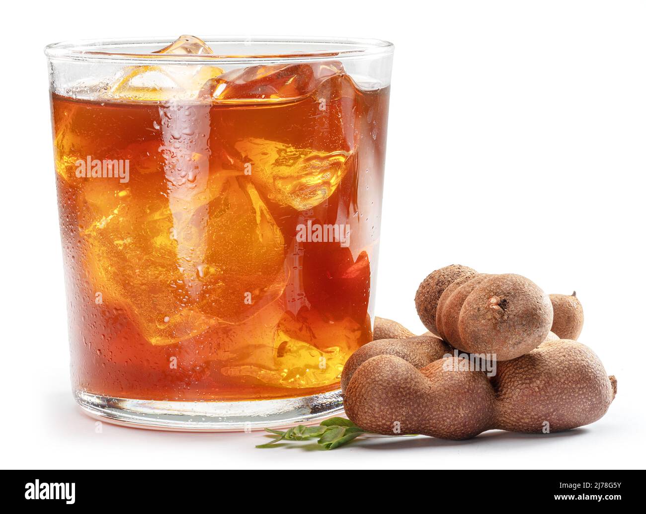 Glass of cool refreshing tamarind drink and some tamarind fruit on ...