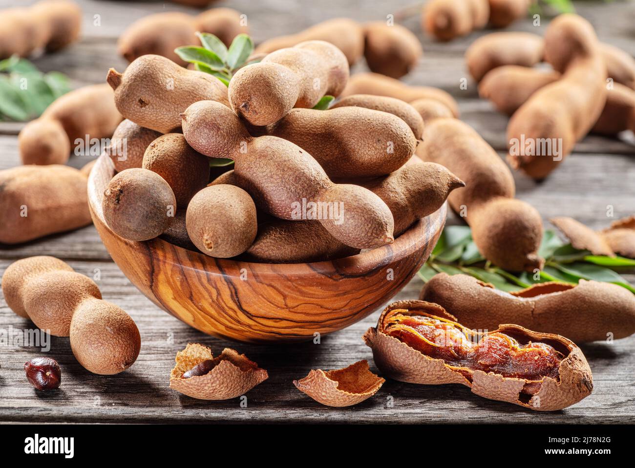 Ripe tamarind fruit, leaves and some tamarind seeds on wooden table ...