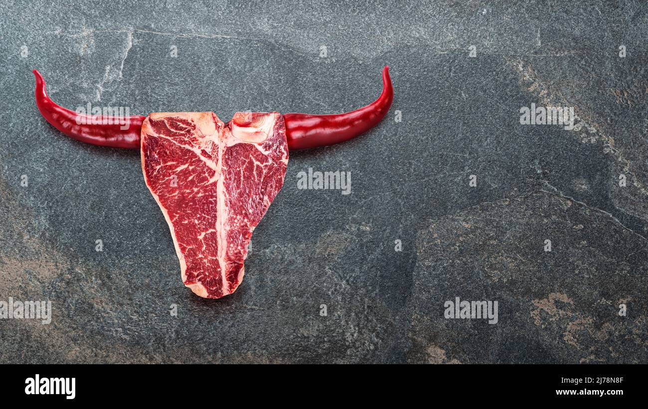 T-bone beef steak and hot peppers arranged in a shape of bull head ...