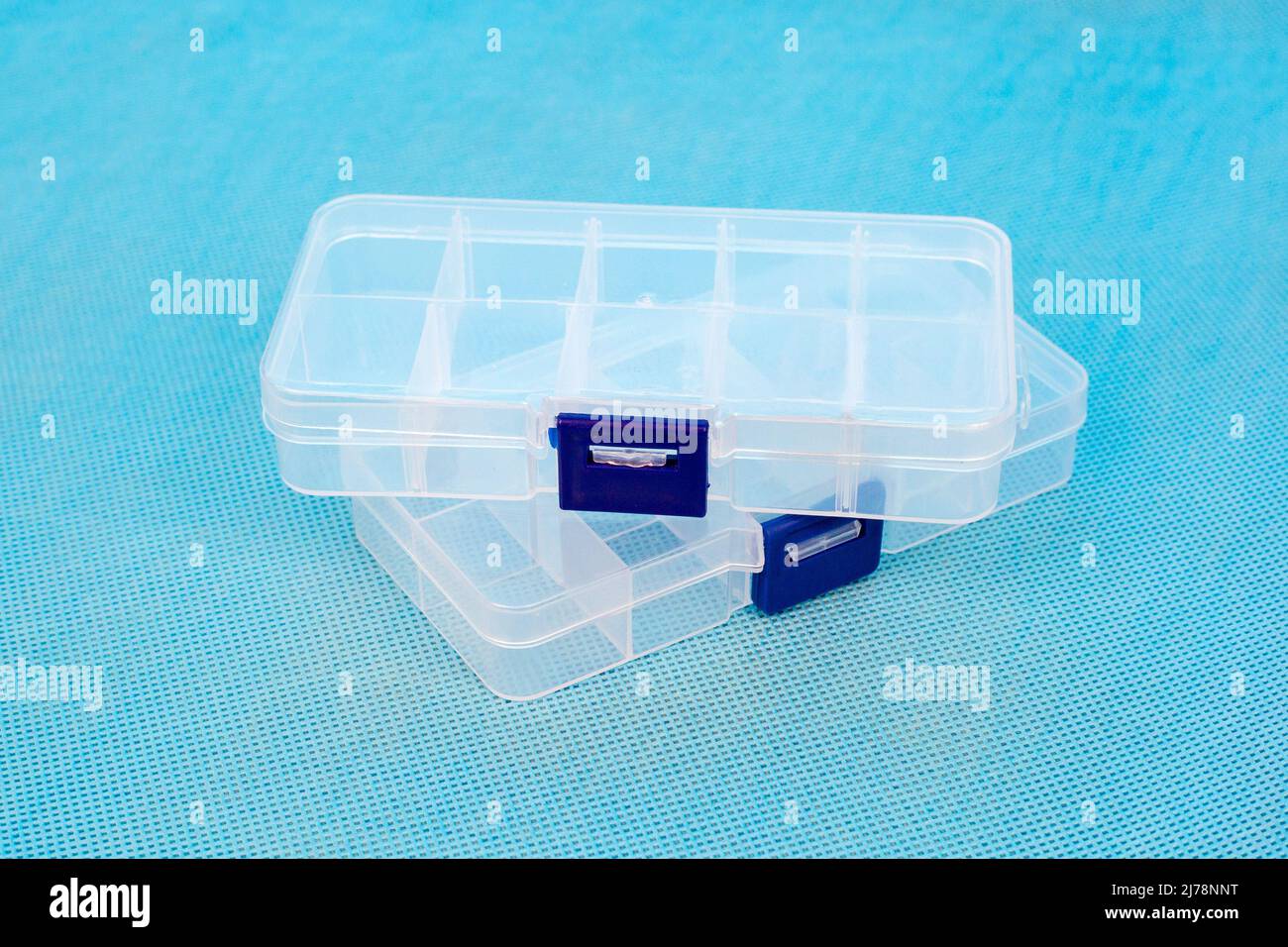 Two plastic boxes with internal cells for storing small items on a blue ...