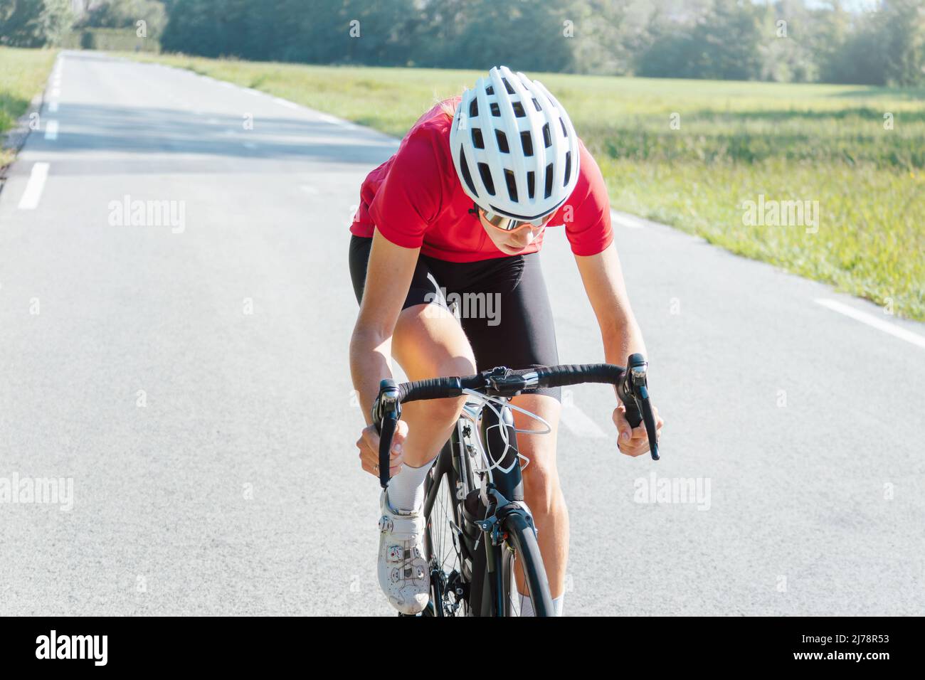 Young Caucasian female bicyclist in speed sprint position on the bike ...