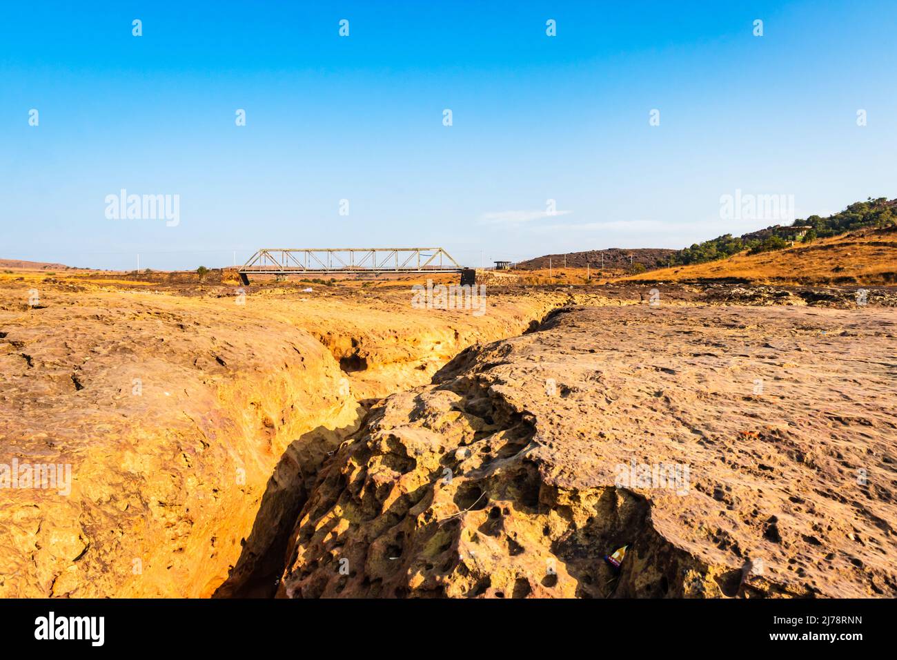 dry river rock cracks with vintage iron bridge and blue sky at morning ...