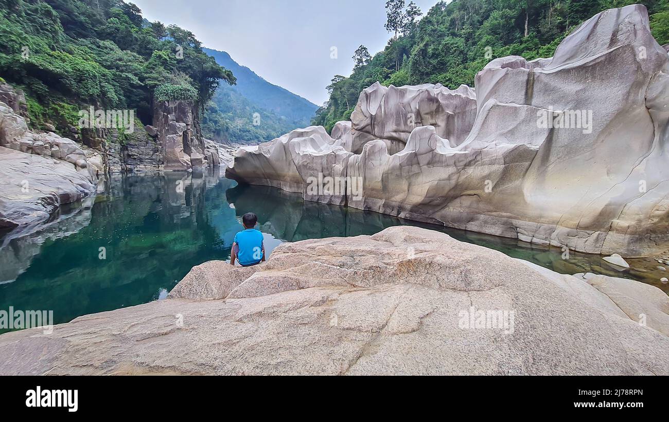 isolated young child sitting on naturally formed white shiny stone in ...