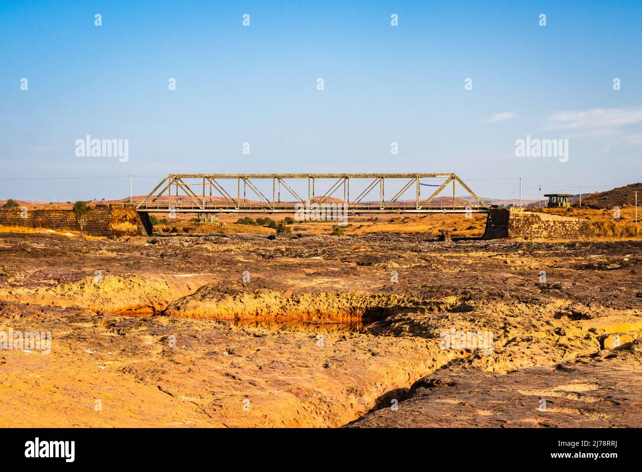 dry river rock cracks with vintage iron bridge and blue sky at morning ...