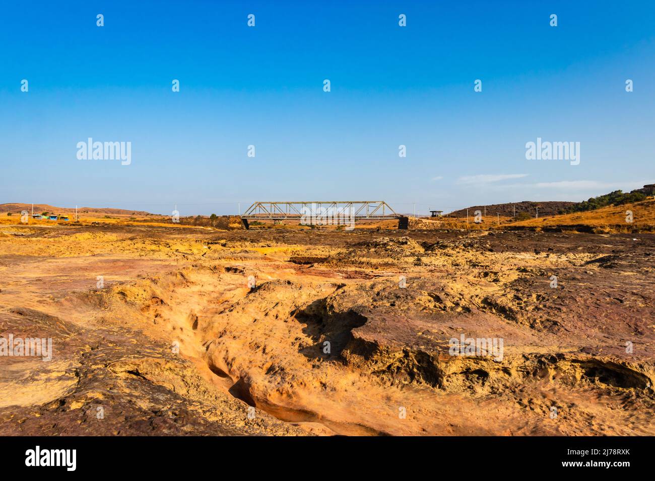 dry river rock cracks with vintage iron bridge and blue sky at morning ...