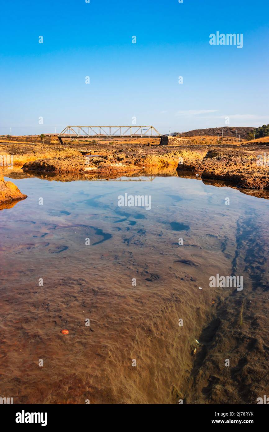dry river rock formation with water and vintage iron bridge and blue ...