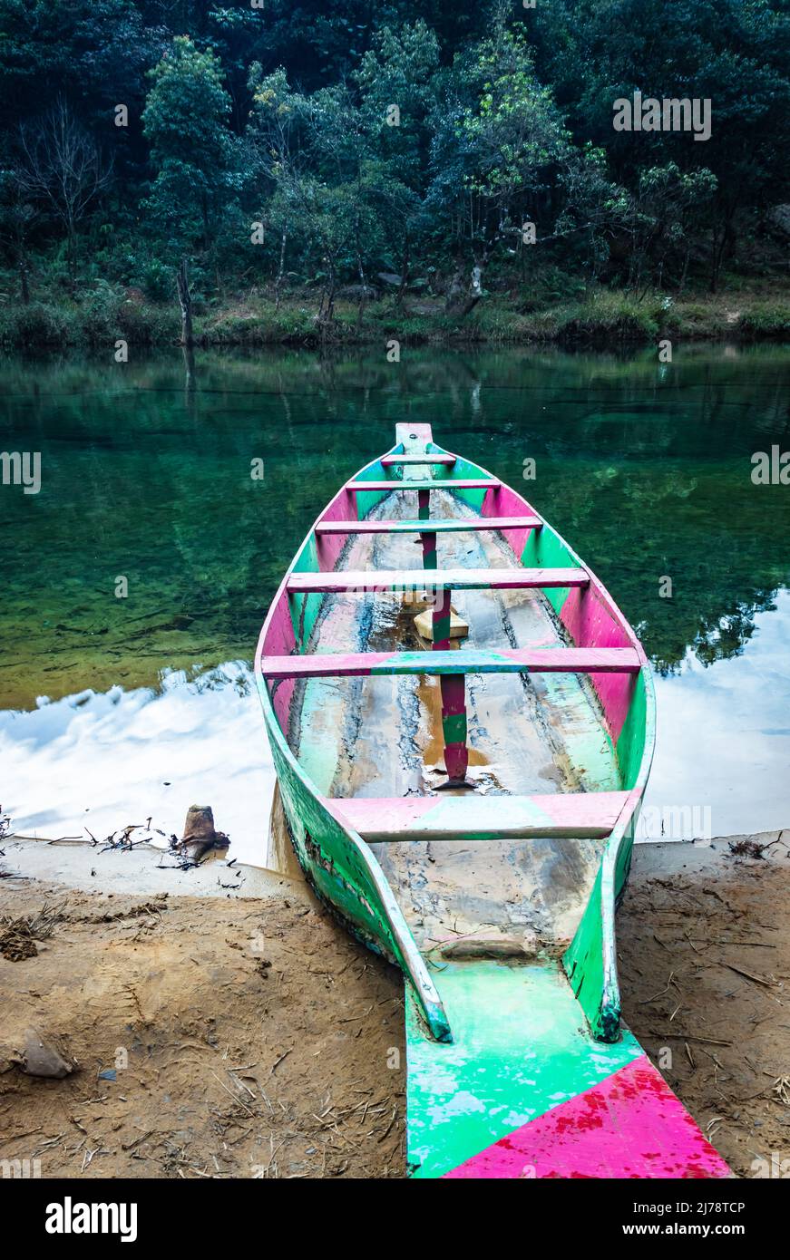 isolated wood boat at river shore surrounded by dense green forests at ...