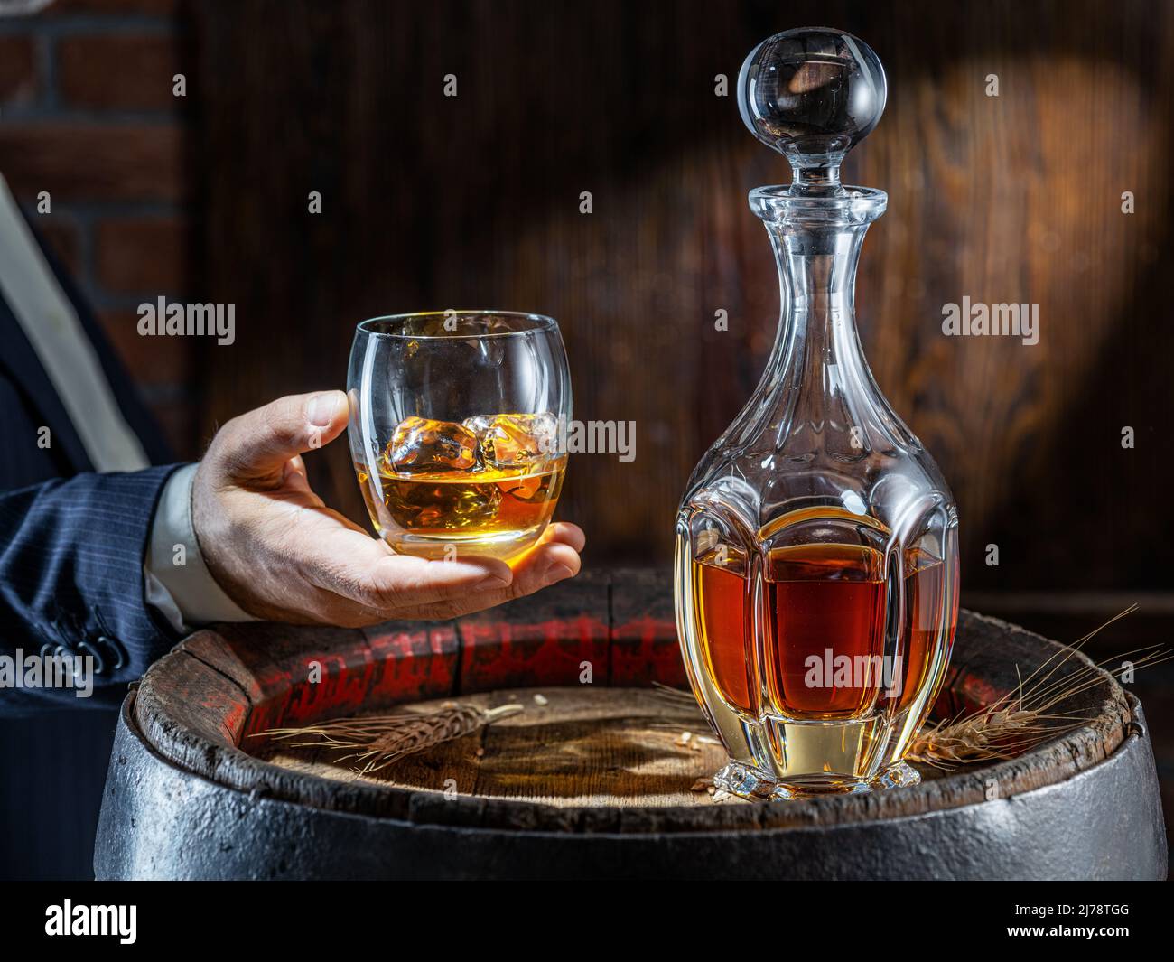 Whisky tasting. Man sits in front of a barrel with a decanter and a ...