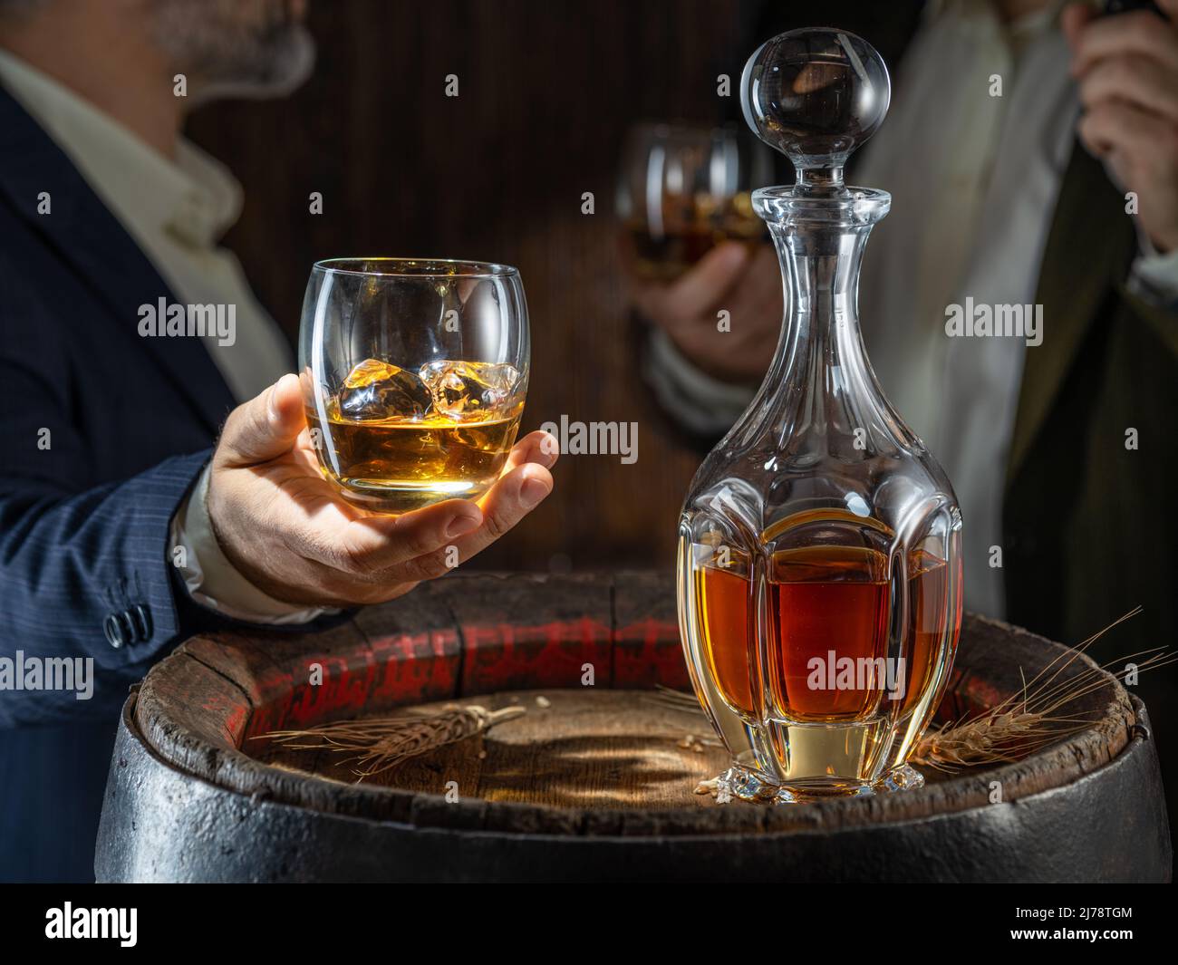 Whisky tasting. Man sits in front of a barrel with a decanter and a ...