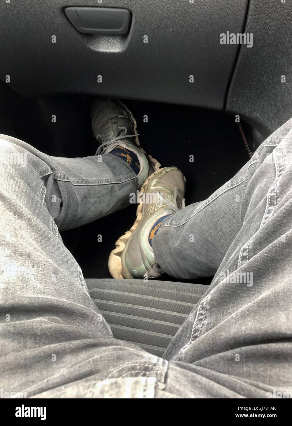 trainer clad feet in footwell of car Stock Photo - Alamy