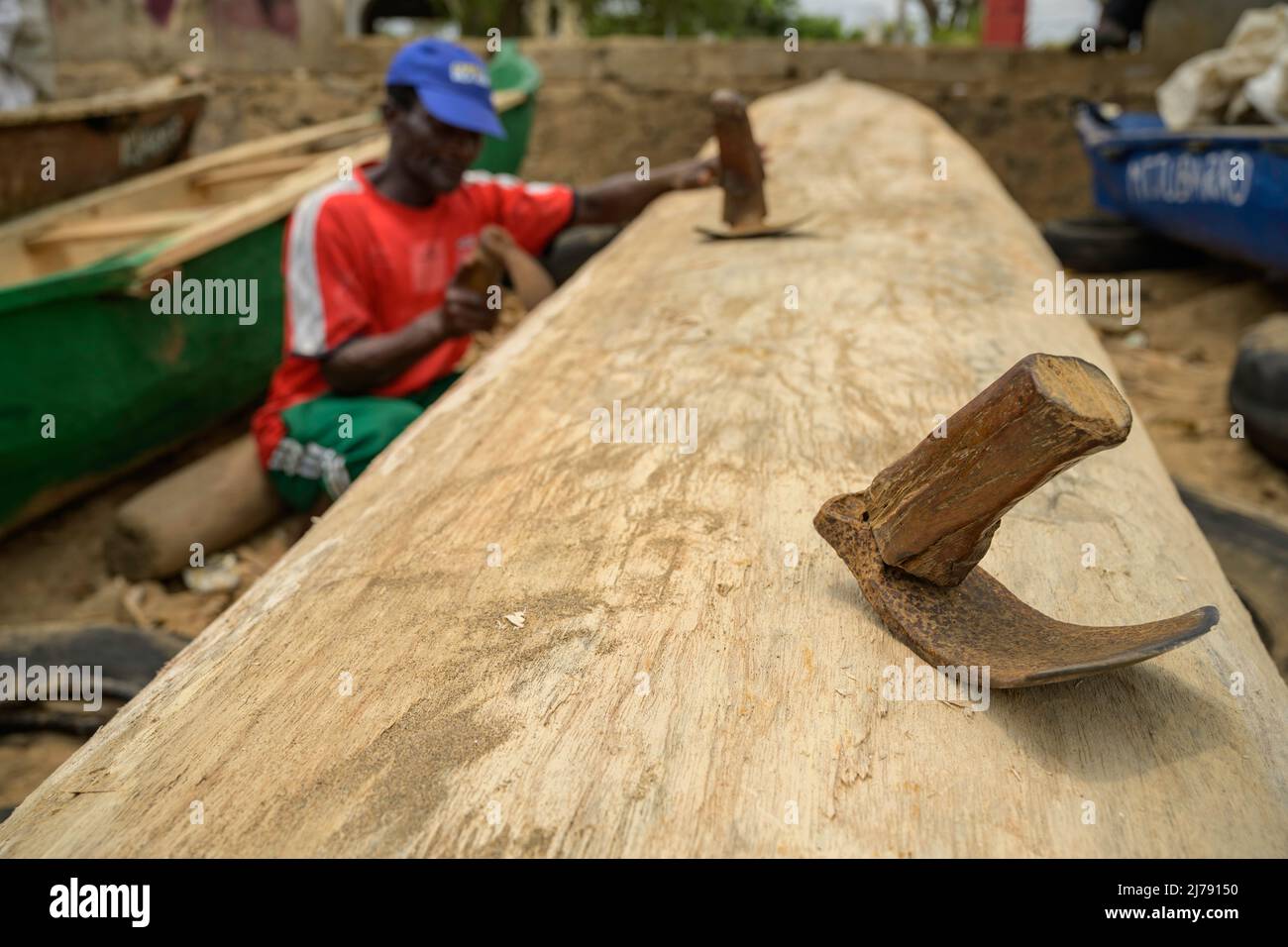 Man hand carving a large log to make a canoe Stock Photo - Alamy