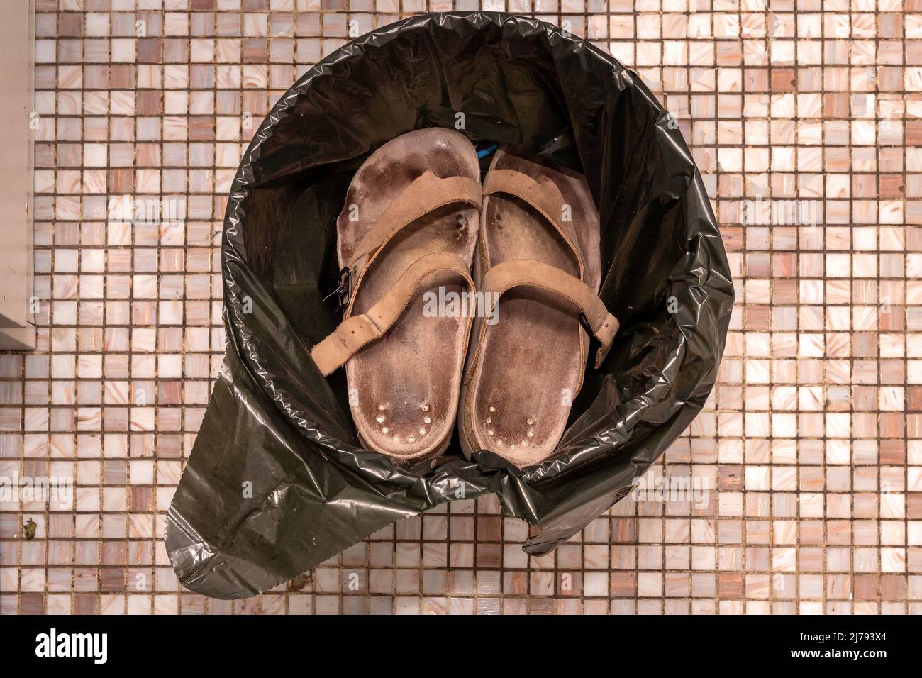 Dirty worn out sandals thrown out in plastic garbage bin inside house ...