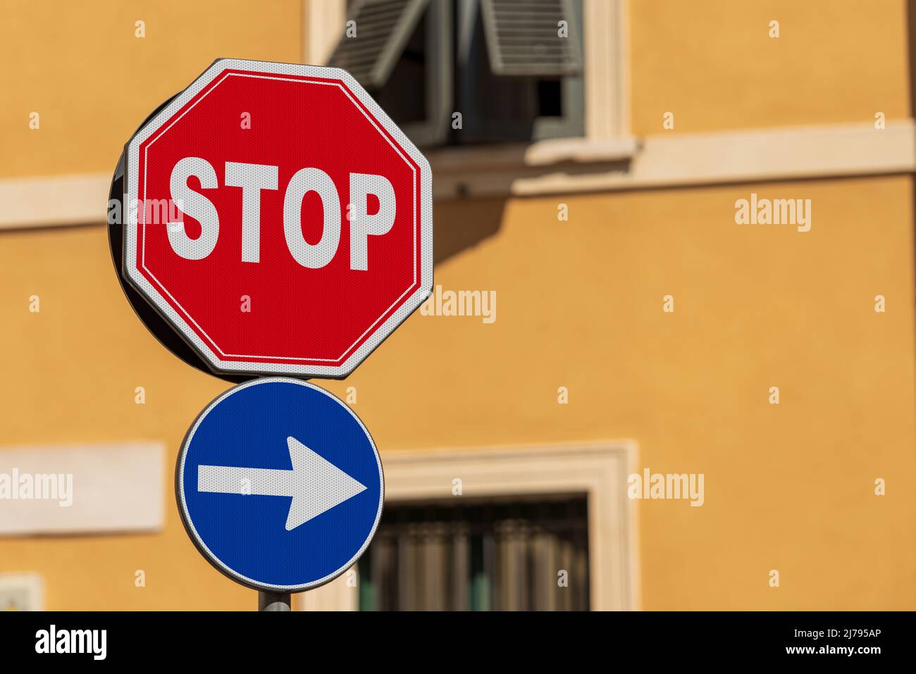 Close-up of an one way and a stop road sign with a residential building ...