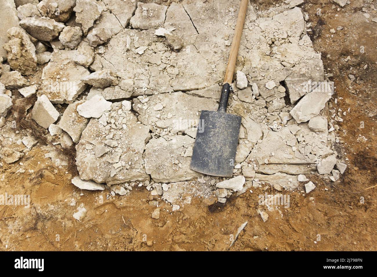 Spade lying on broken concrete floor Stock Photo - Alamy