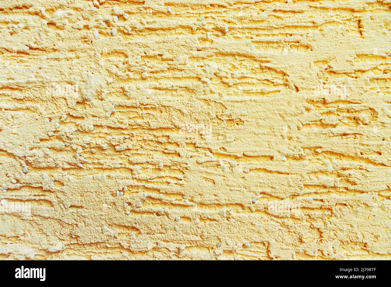 The yellow texture of the plaster of the exterior wall of the building ...