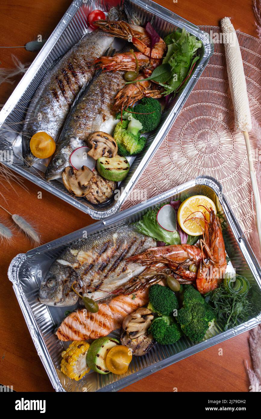 two foil packages with fried fish steaks and shrimp Stock Photo - Alamy