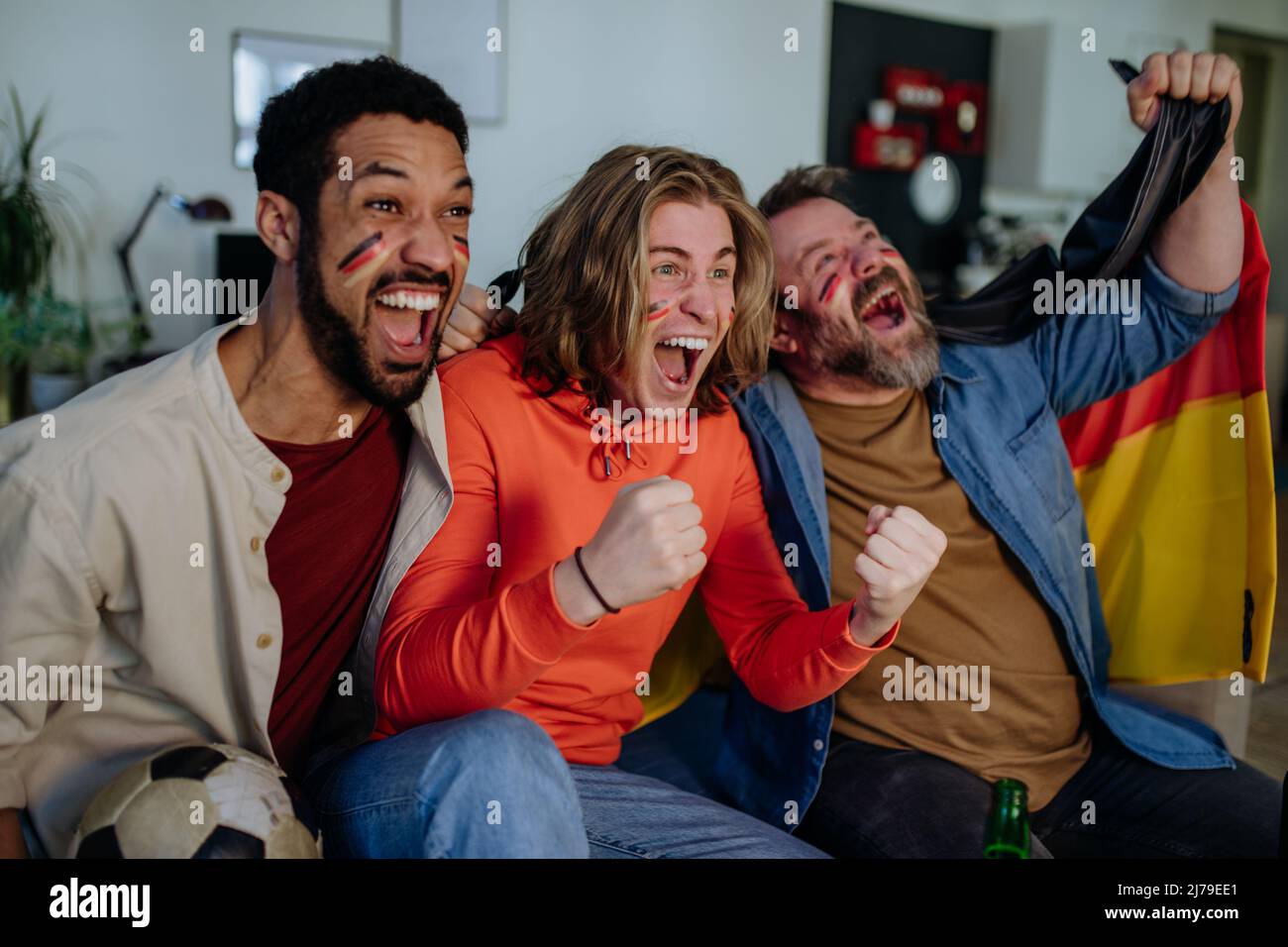 Happy German football fans friends watching football at home and ...