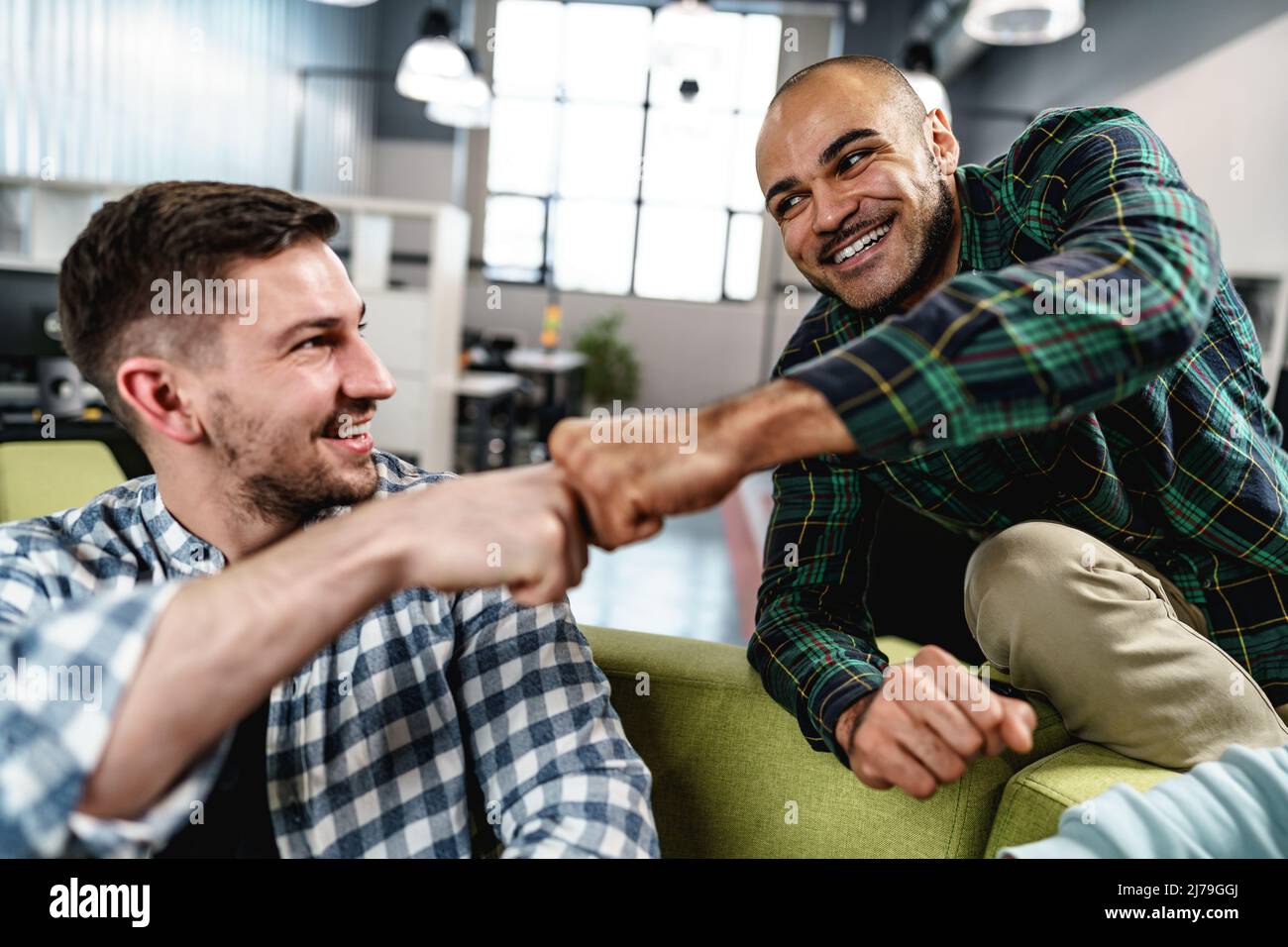 Two handsome men sitting together in the office and giving each other a ...