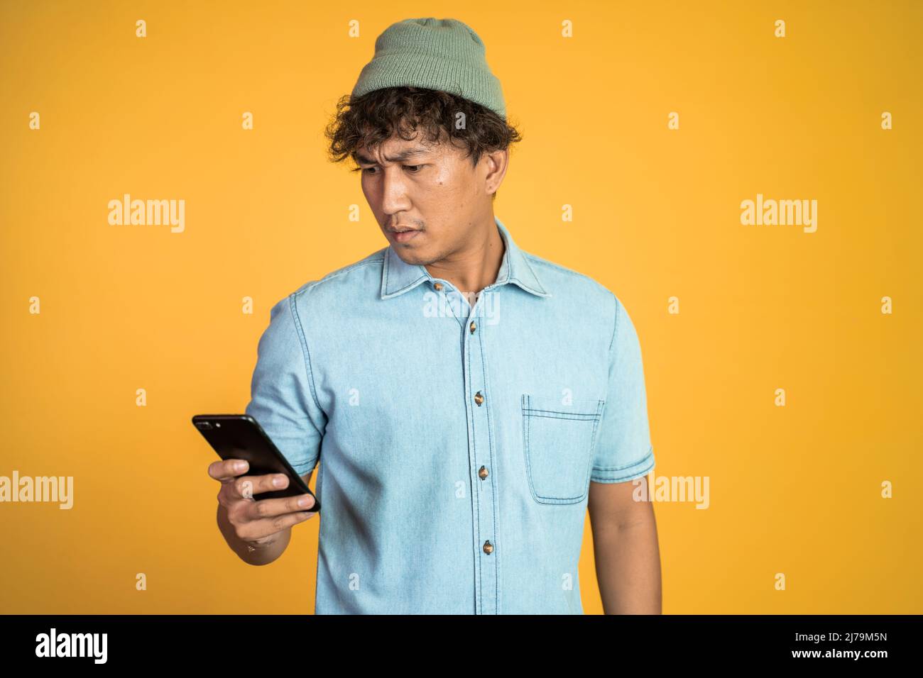 asian young man looking at the screen of a mobile phone Stock Photo - Alamy