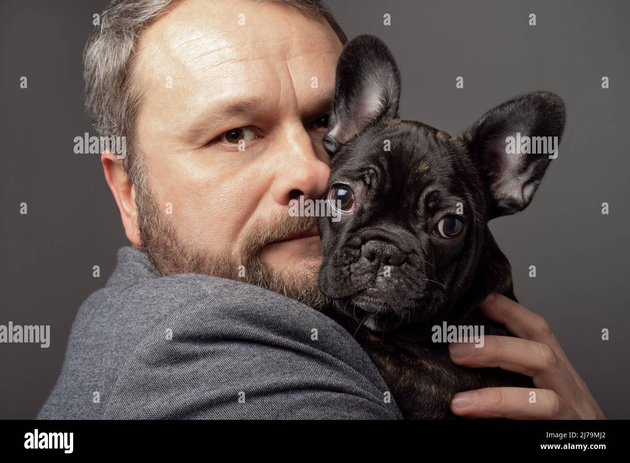 Man hugging a young Female Puppy of a French Bulldog. Concept of care ...